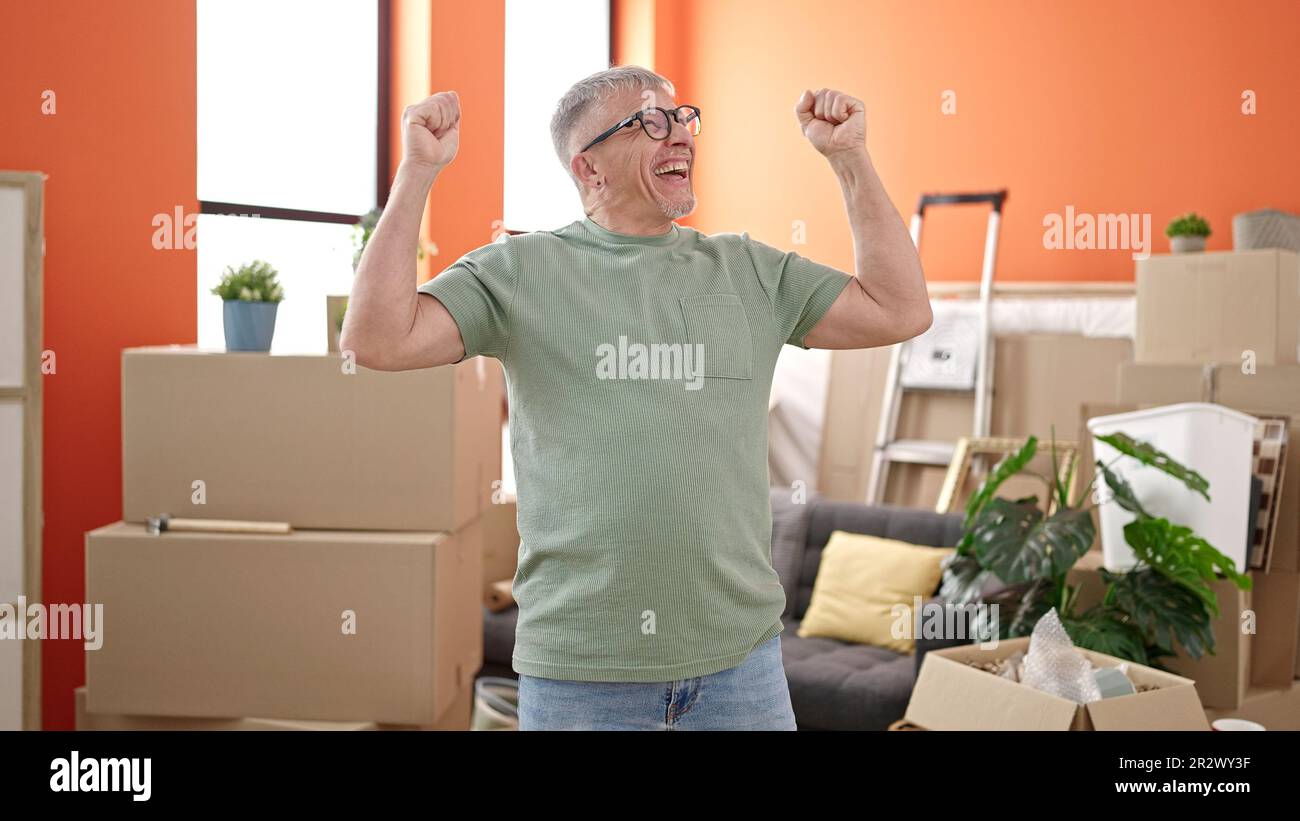 Middle age grey-haired man standing with celebration gesture at new ...
