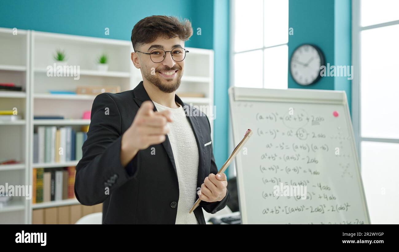 Young arab man teacher teaching maths lesson pointing with finger to ...