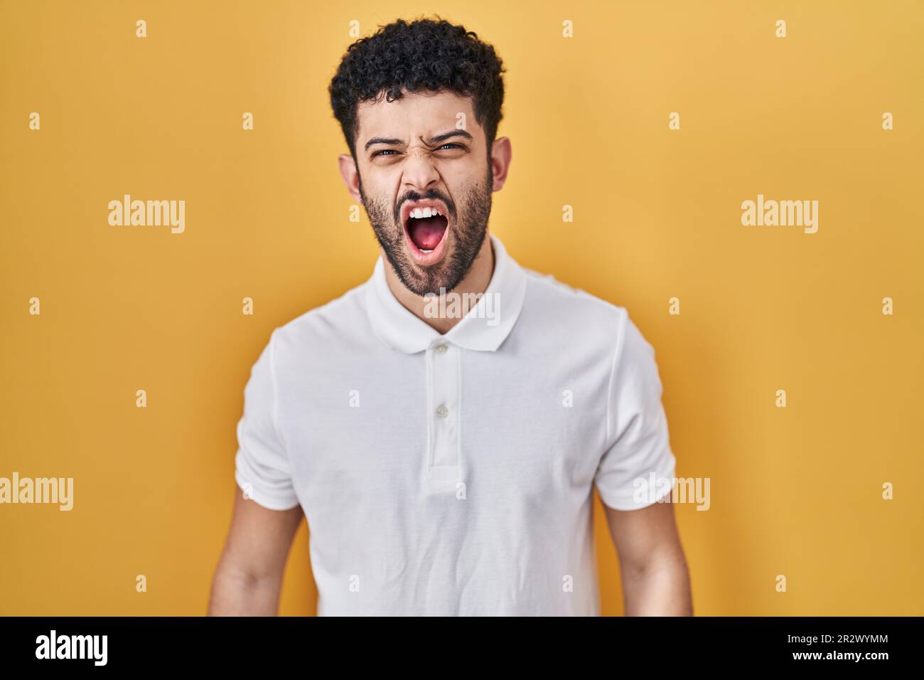 Arab man standing over yellow background angry and mad screaming ...