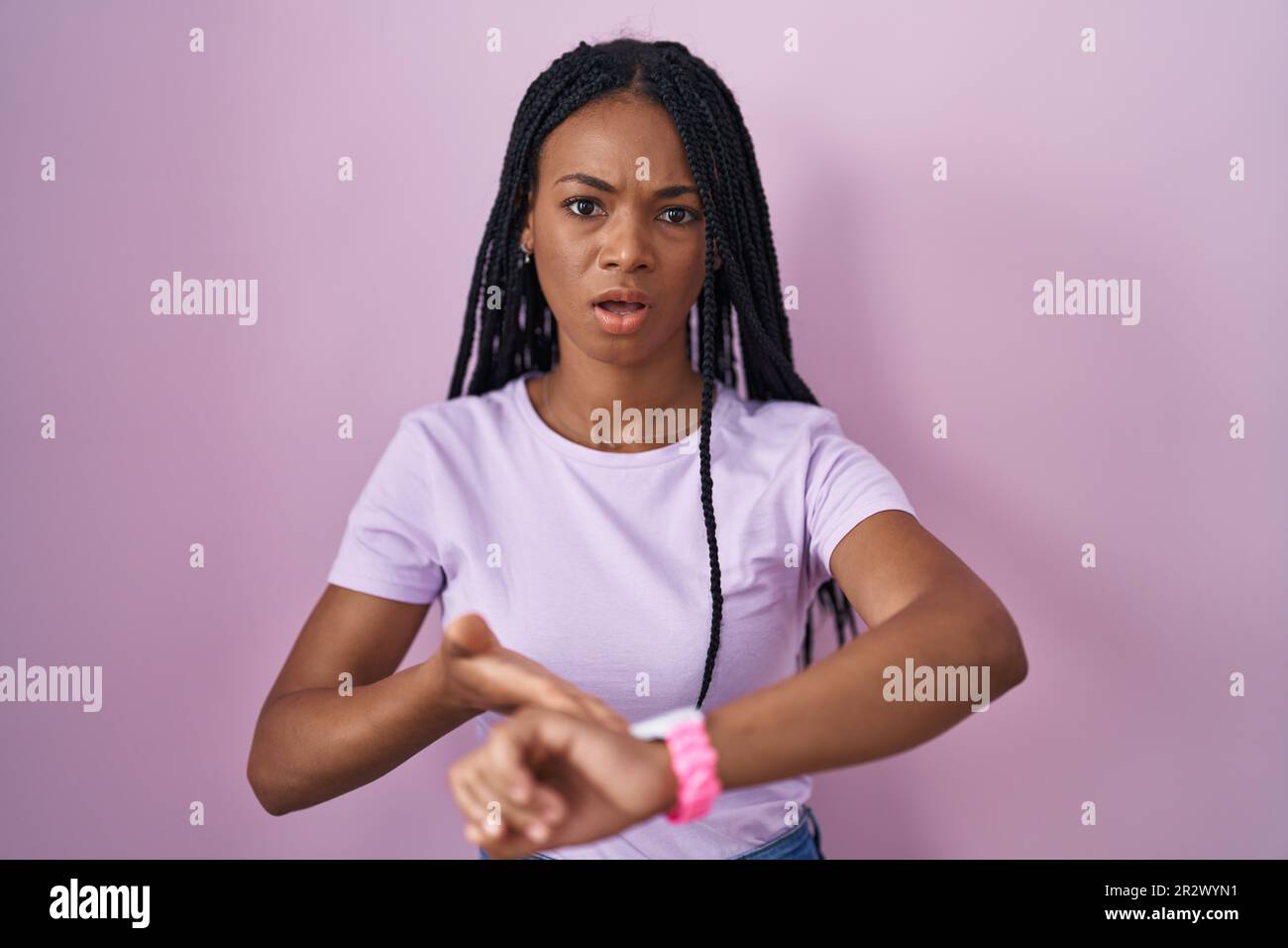 African american woman with braids standing over pink background in ...