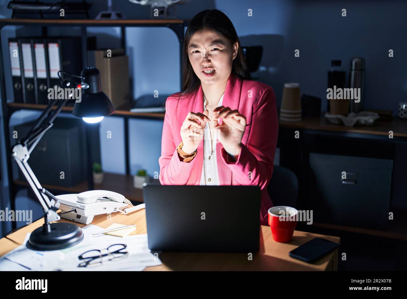 Chinese young woman working at the office at night disgusted expression ...