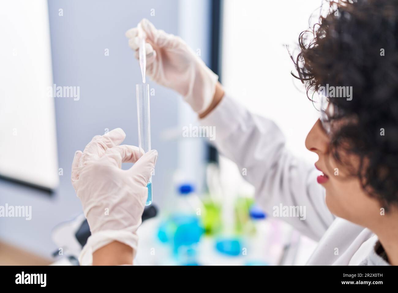 Young middle east woman scientist pouring liquid on test tube at ...