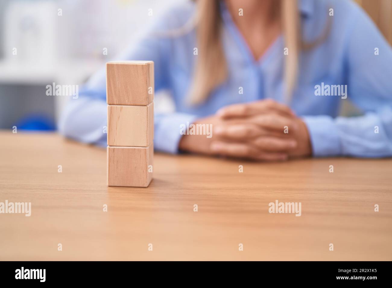 Young blonde woman business worker sitting on table with wooden cubes ...