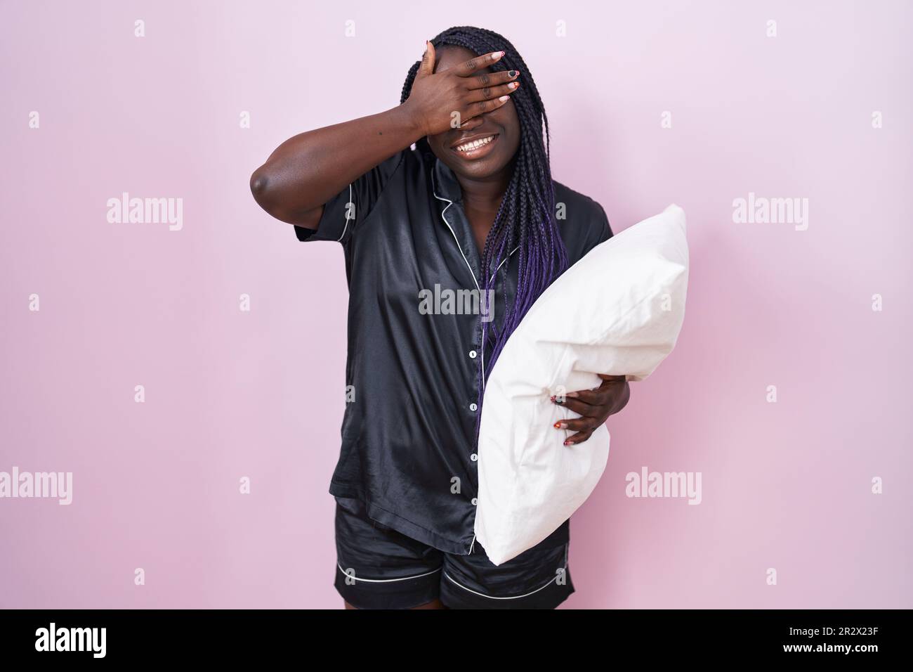Young african woman wearing pijama hugging pillow smiling and laughing ...