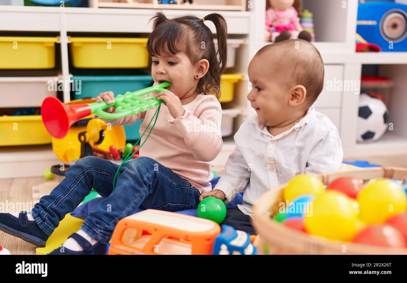 Adorable boy and girl playing trumpet holding balls at kindergarten ...