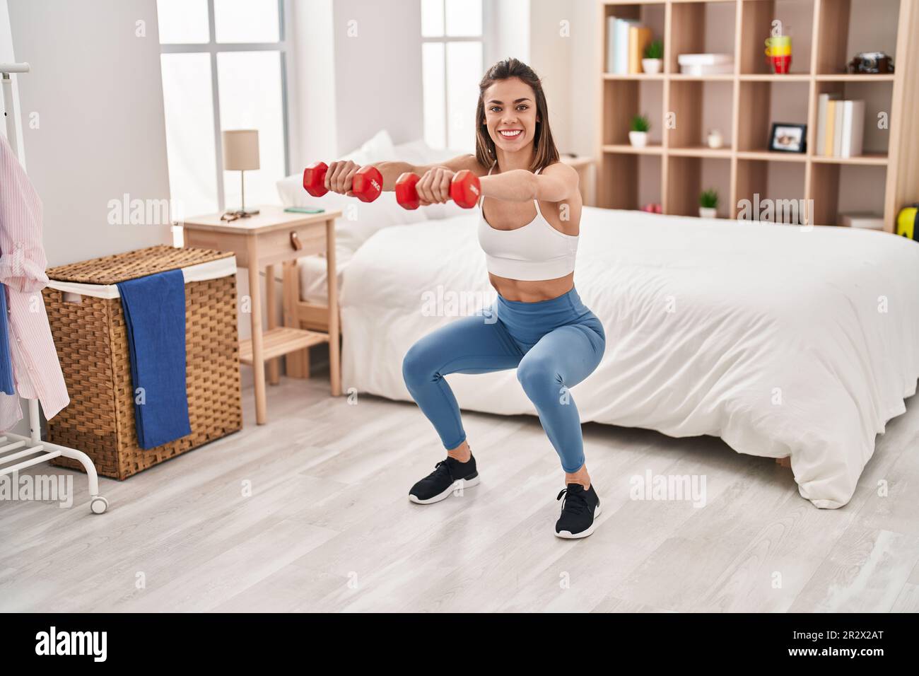 Young beautiful hispanic woman training leg exercise using dumbbells at ...