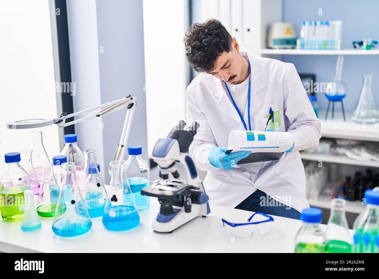 Young caucasian man scientist reading report working at laboratory ...
