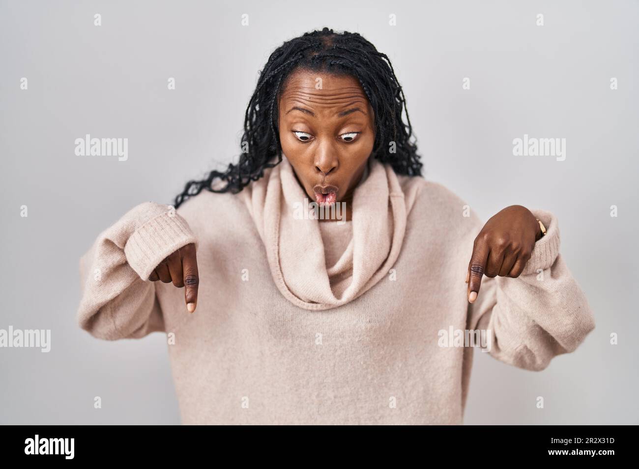 African woman standing over white background pointing down with fingers ...
