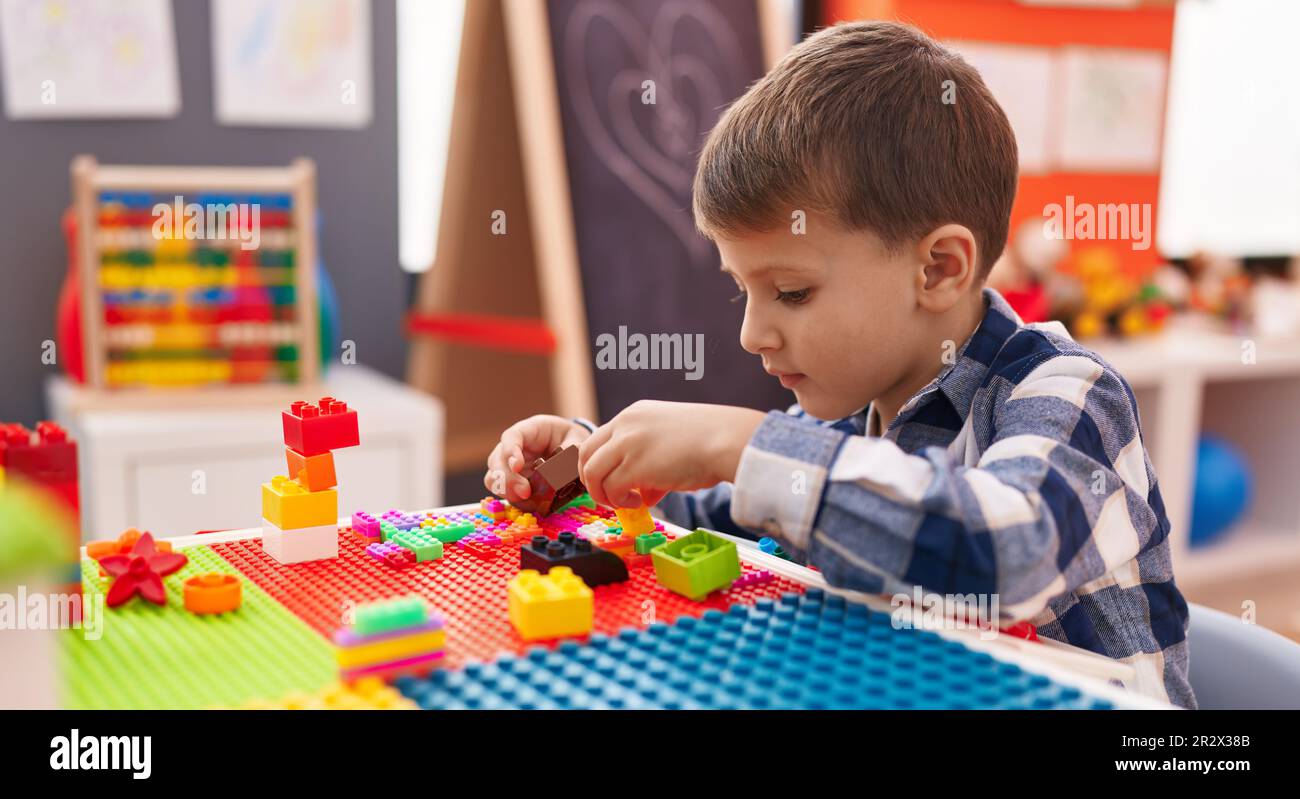 Adorable caucasian boy playing with construction blocks sitting on ...