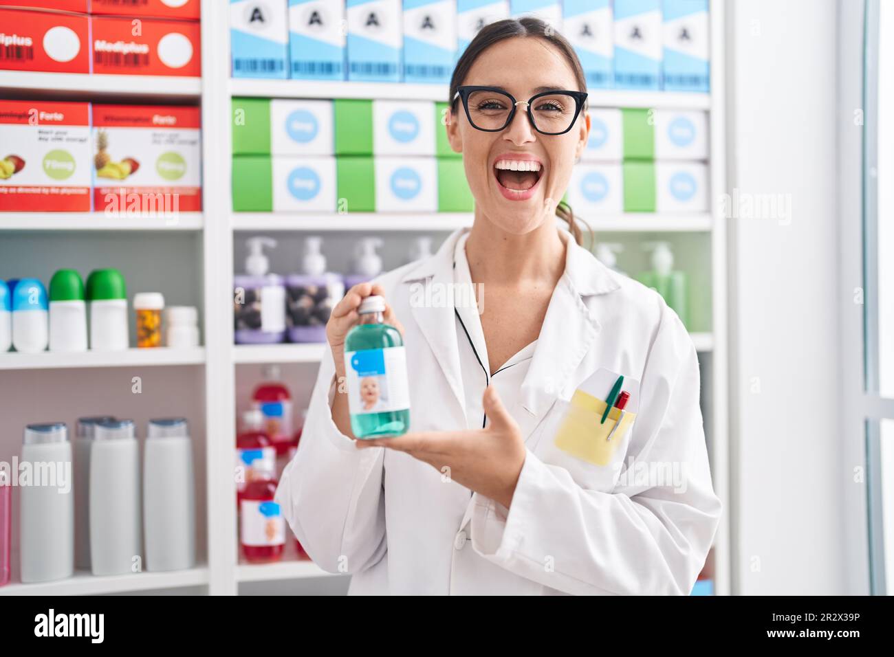 Brunette woman working at pharmacy drugstore holding cough syrup ...