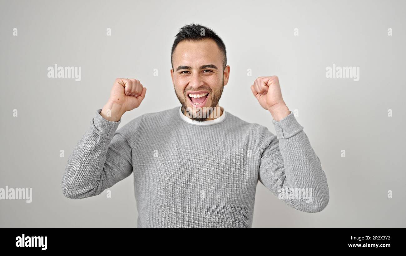 Hispanic man standing with winner expression over isolated white ...