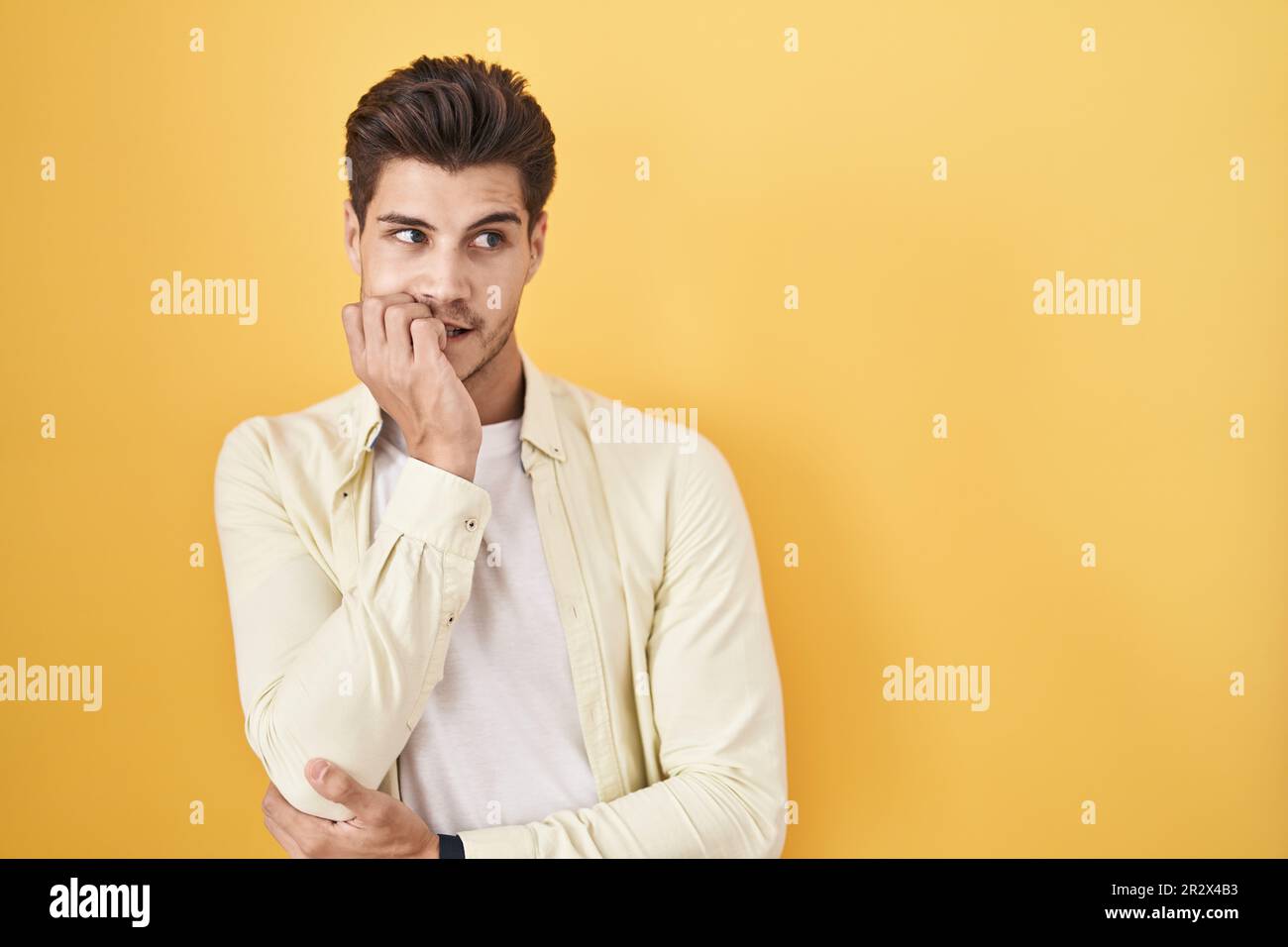 Young hispanic man standing over yellow background looking stressed and ...
