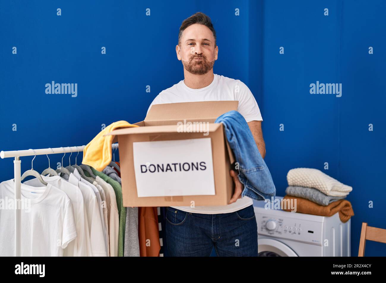 Middle age caucasian man holding donations box puffing cheeks with ...