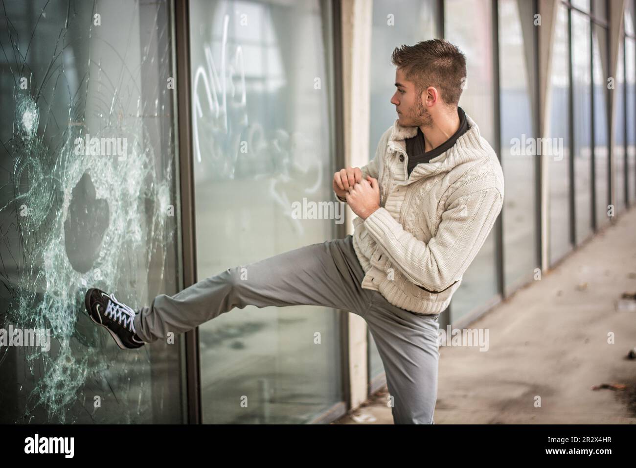 Young man kicking glass showcase on street Stock Photo - Alamy