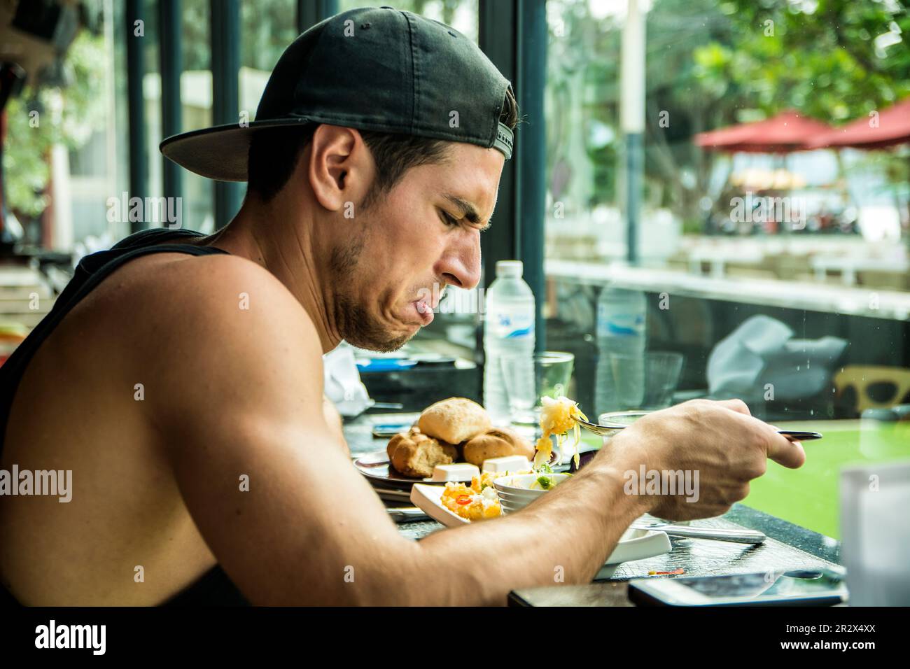 Unhappy young man eating food in a cafe Stock Photo - Alamy