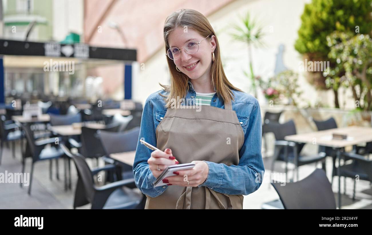 Young blonde woman waitress smiling confident taking notes at coffee ...