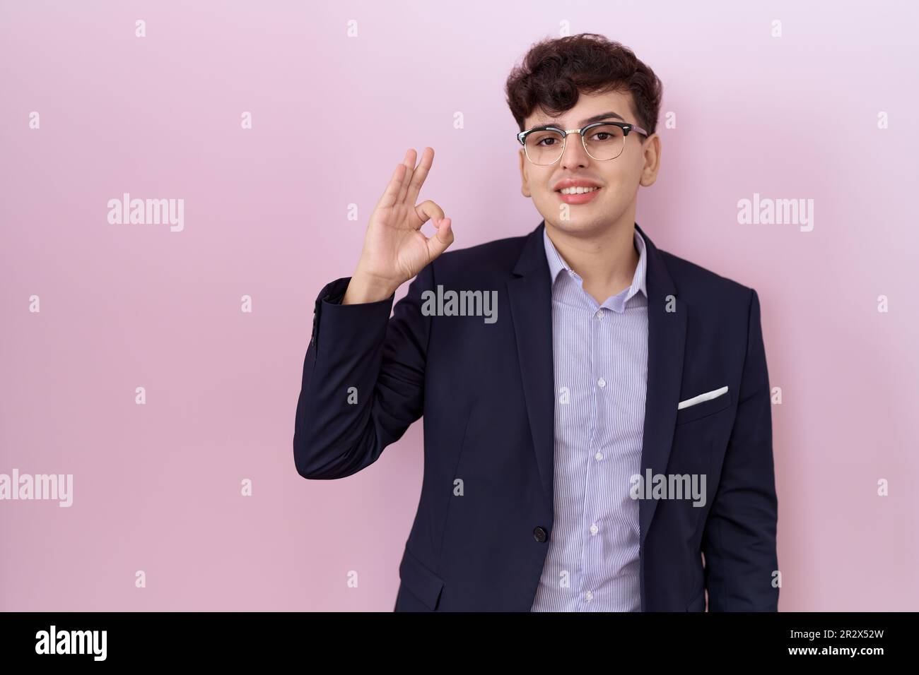 Young non binary man with beard wearing suit and tie smiling positive ...
