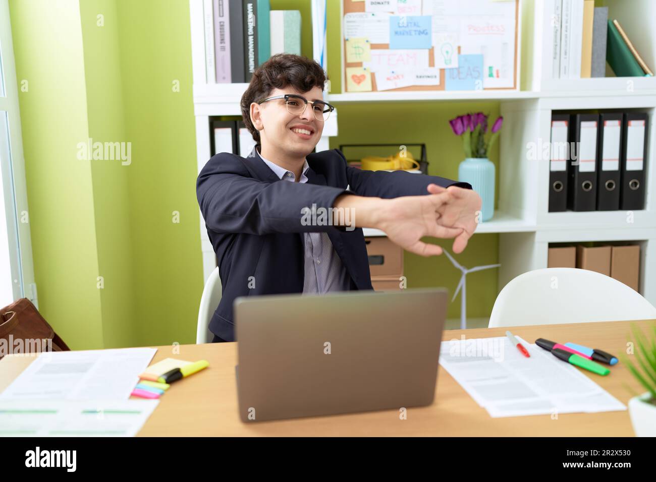 Non binary man business worker stretching arms relaxing at office Stock ...