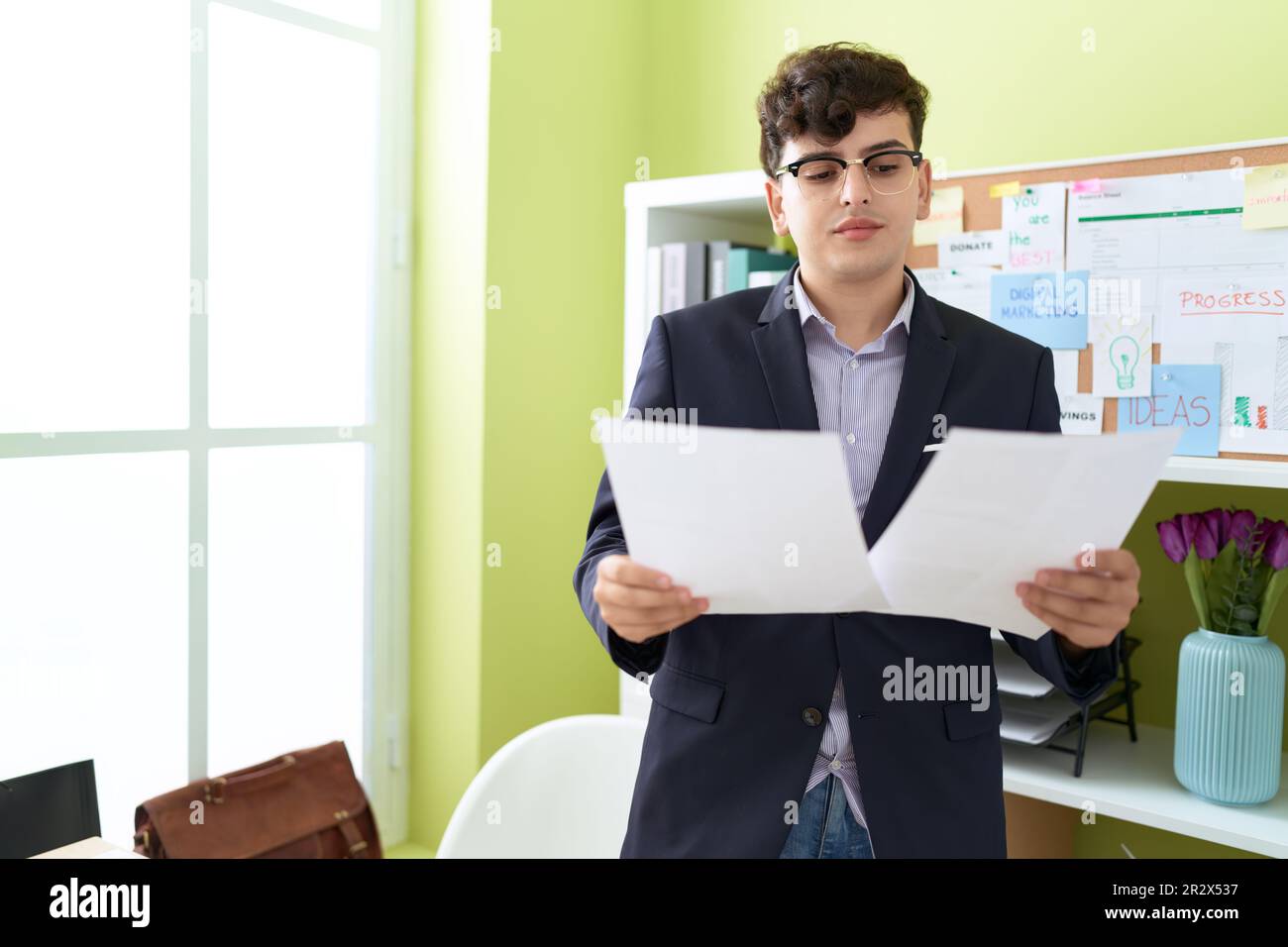 Non binary man business worker reading document at office Stock Photo ...