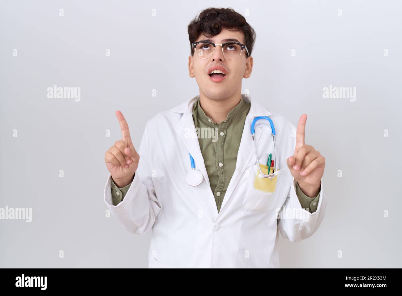 Young non binary man wearing doctor uniform and stethoscope amazed and ...
