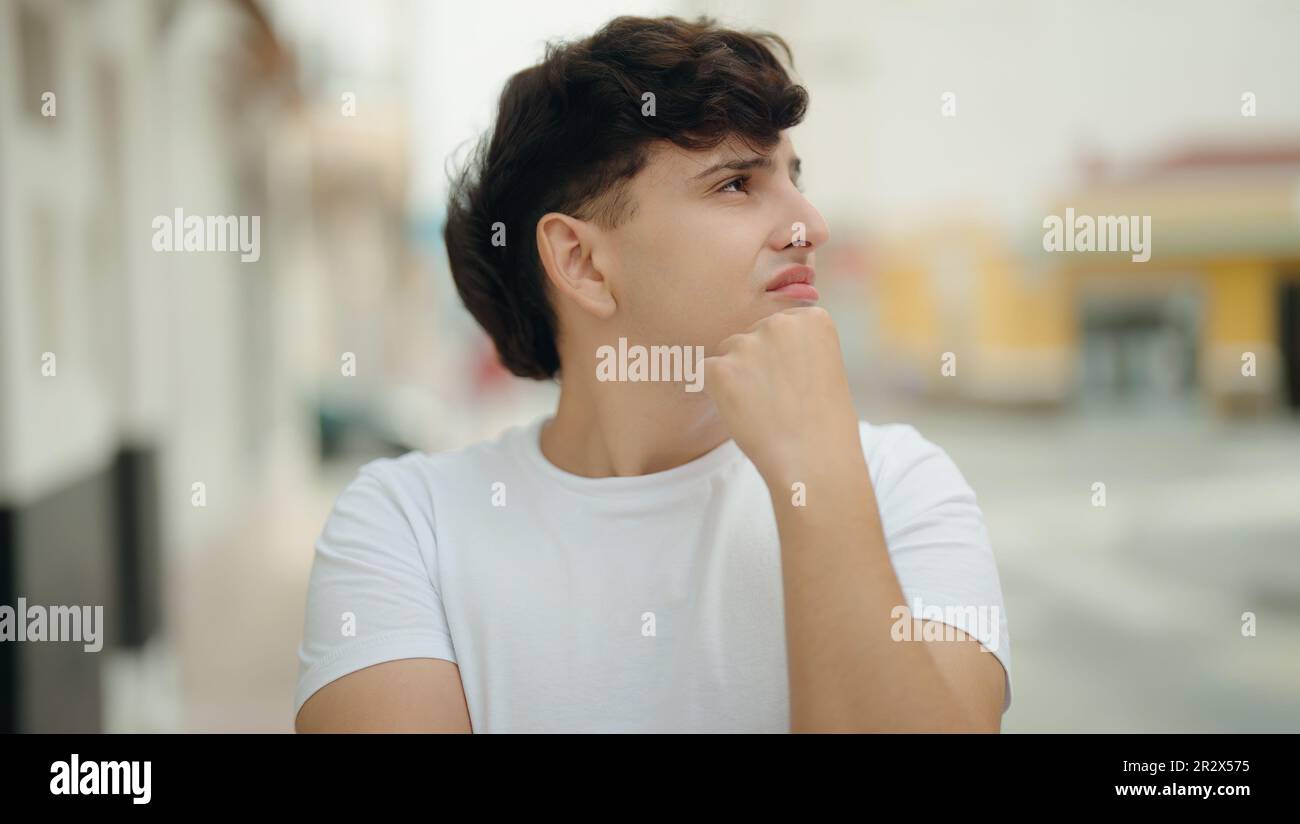 Non binary man standing with doubt expression at street Stock Photo - Alamy