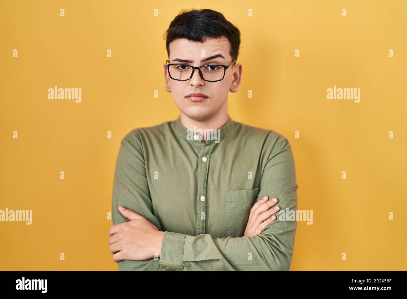 Non binary person standing over yellow background skeptic and nervous ...