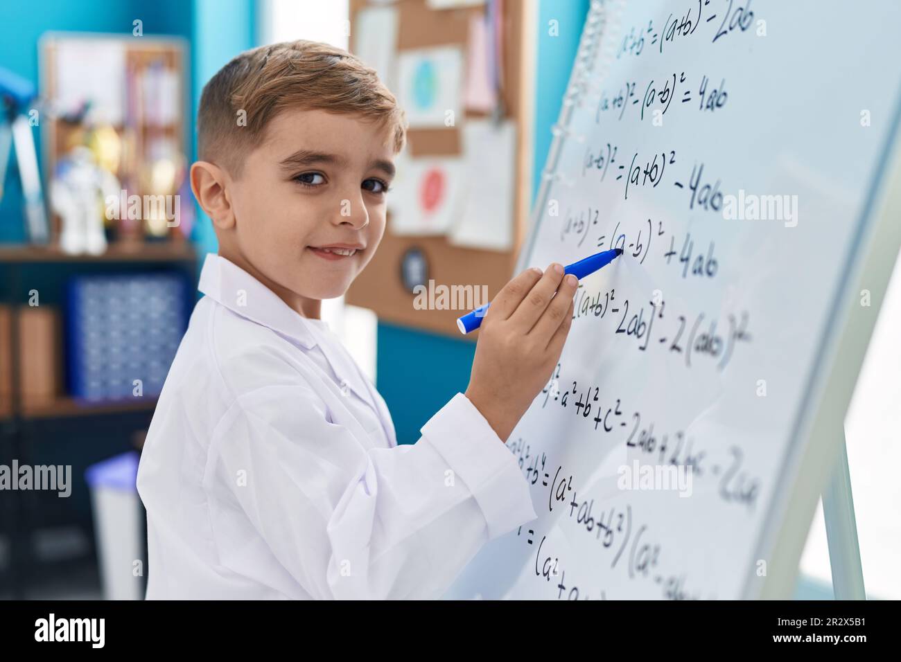 Adorable hispanic boy teaching maths on magnetic board at laboratory ...