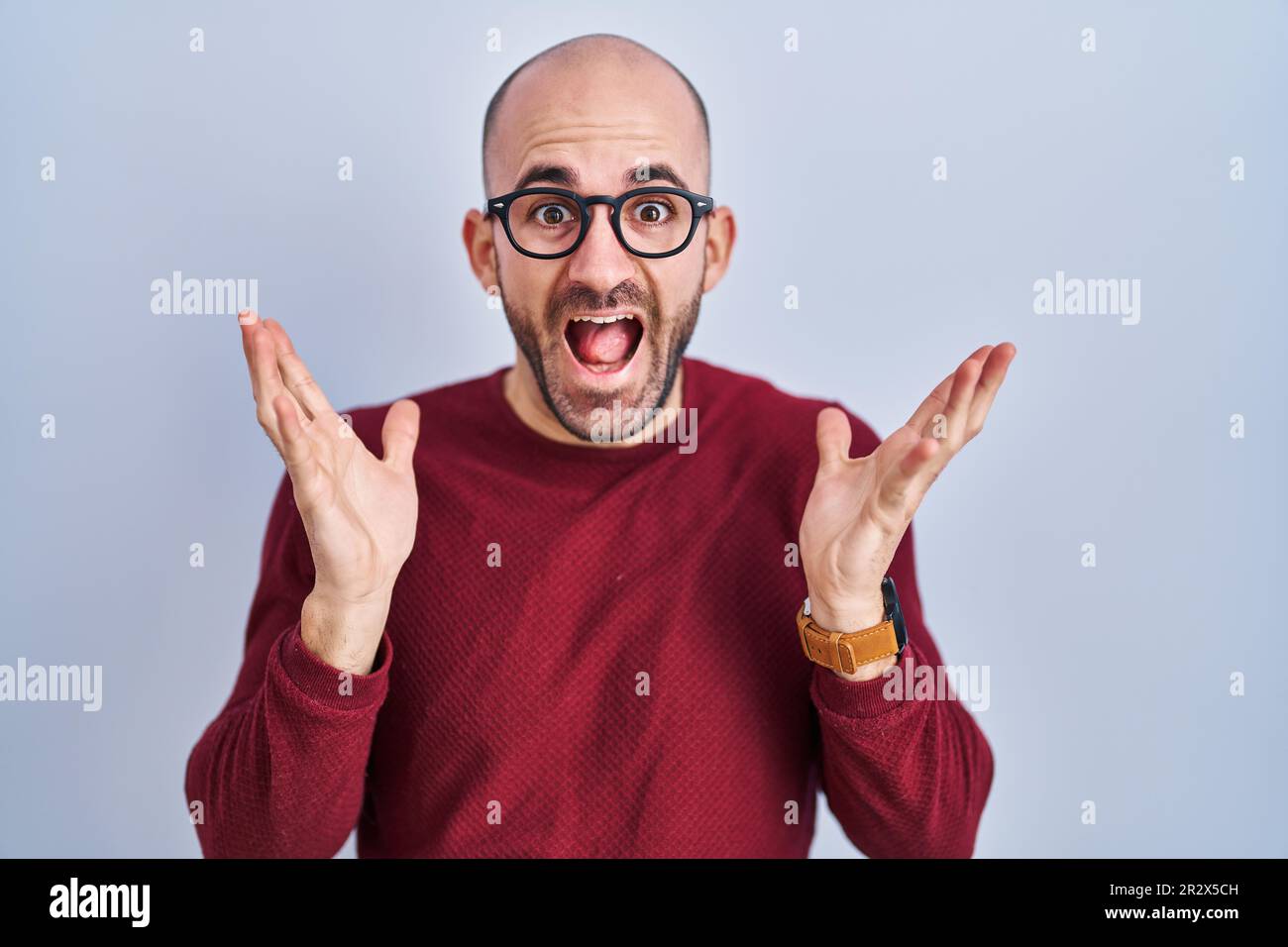 Young bald man with beard standing over white background wearing ...