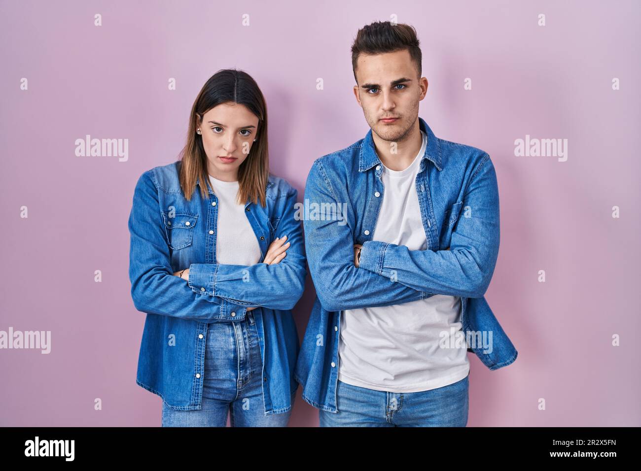 Young hispanic couple standing over pink background skeptic and nervous ...