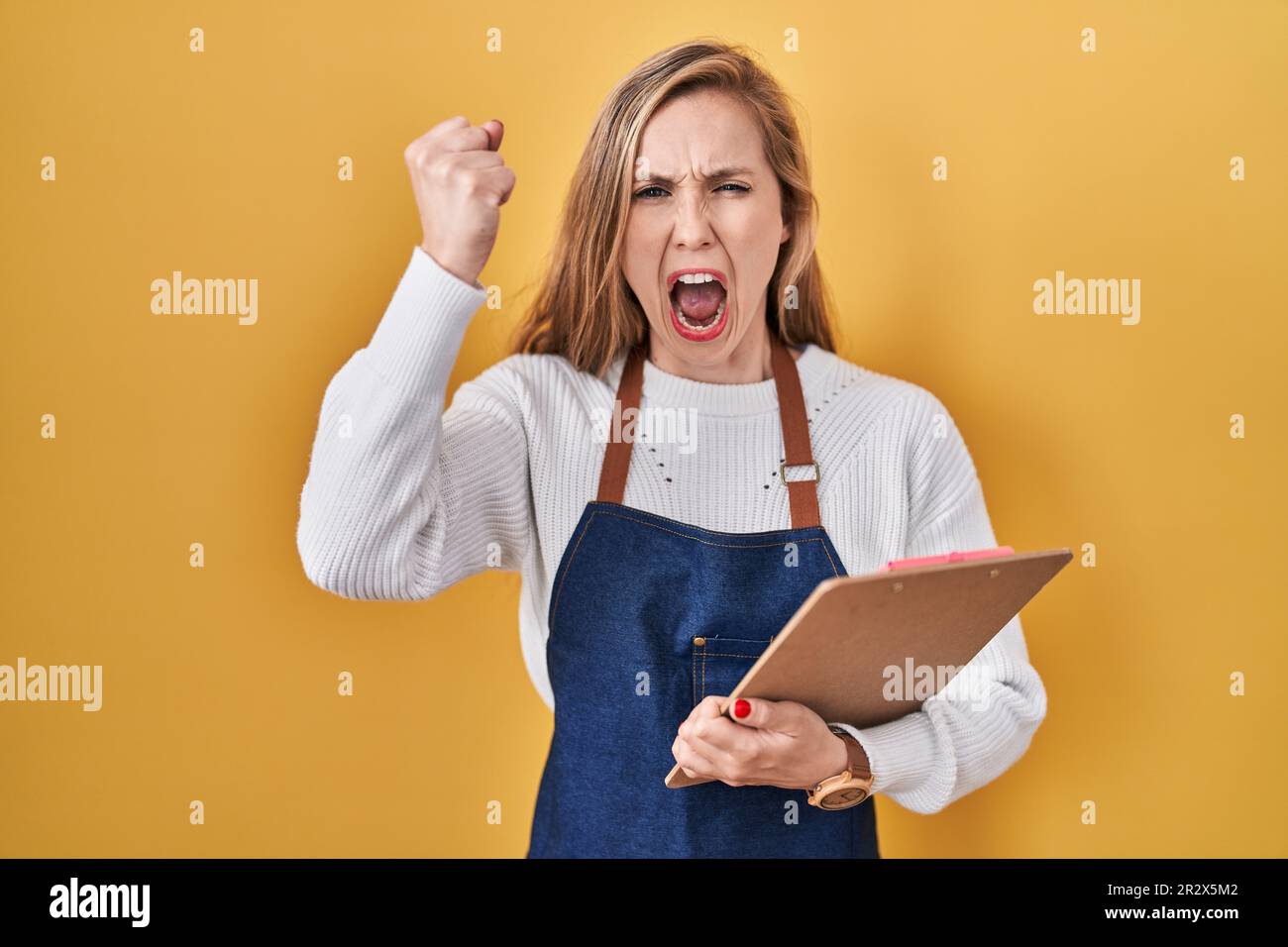 Young blonde woman wearing professional waitress apron holding ...