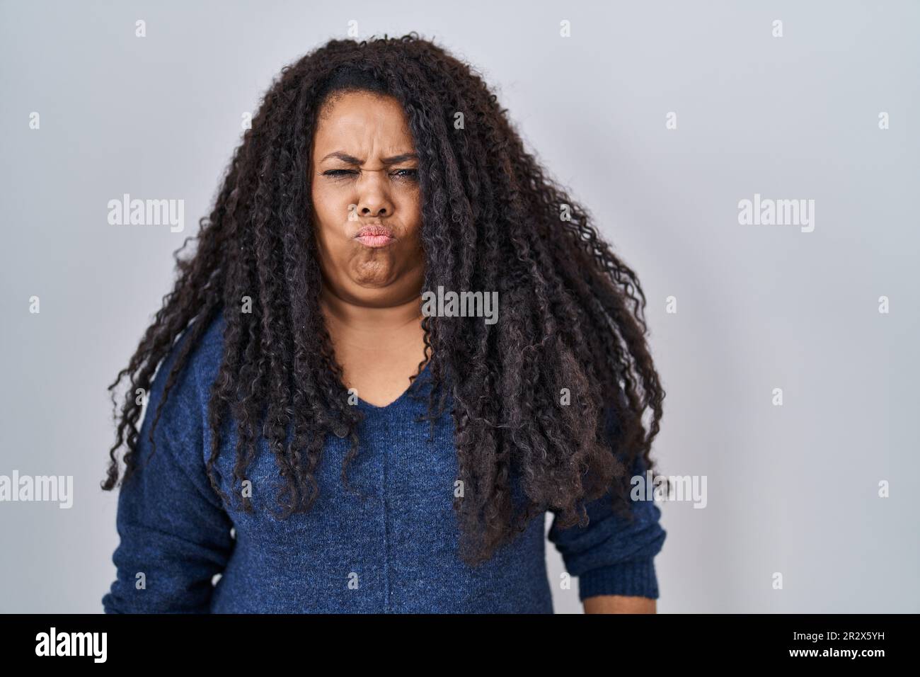 Plus size hispanic woman standing over white background depressed and ...