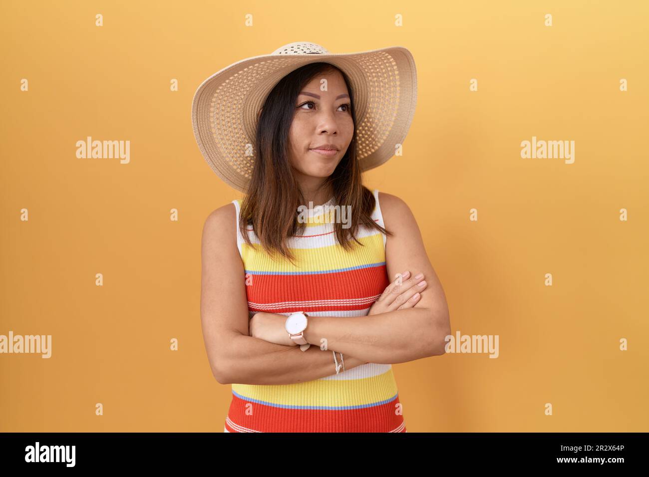 Middle age chinese woman wearing summer hat over yellow background ...