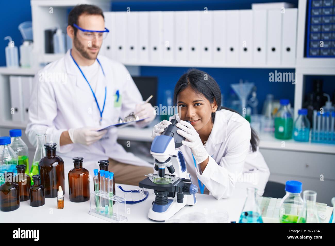 Man and woman scientists using microscope working at laboratory Stock Photo - Alamy