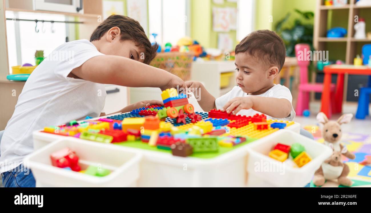 Adorable boys playing with construction blocks sitting on table at ...