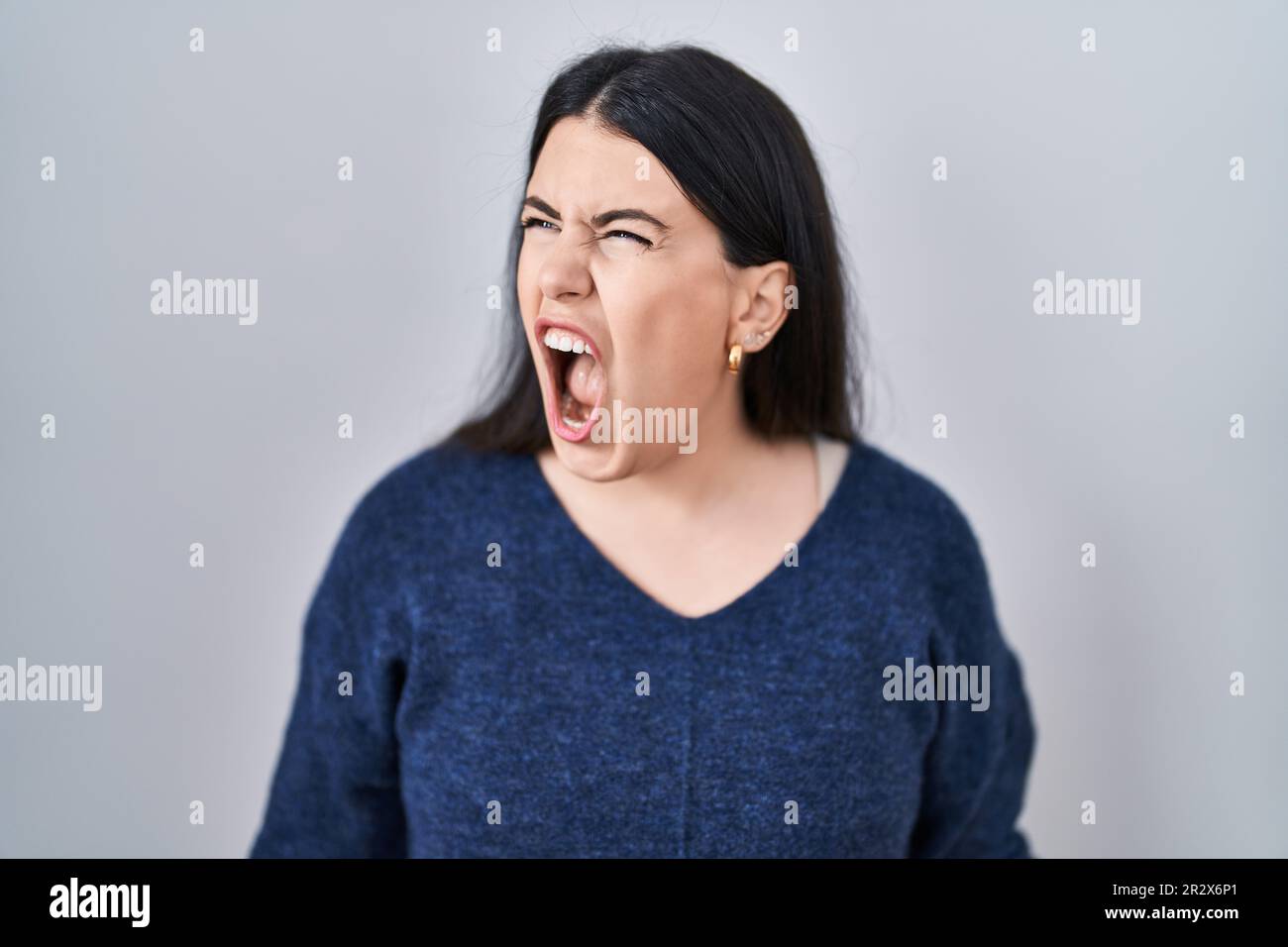 Young brunette woman standing over isolated background angry and mad ...