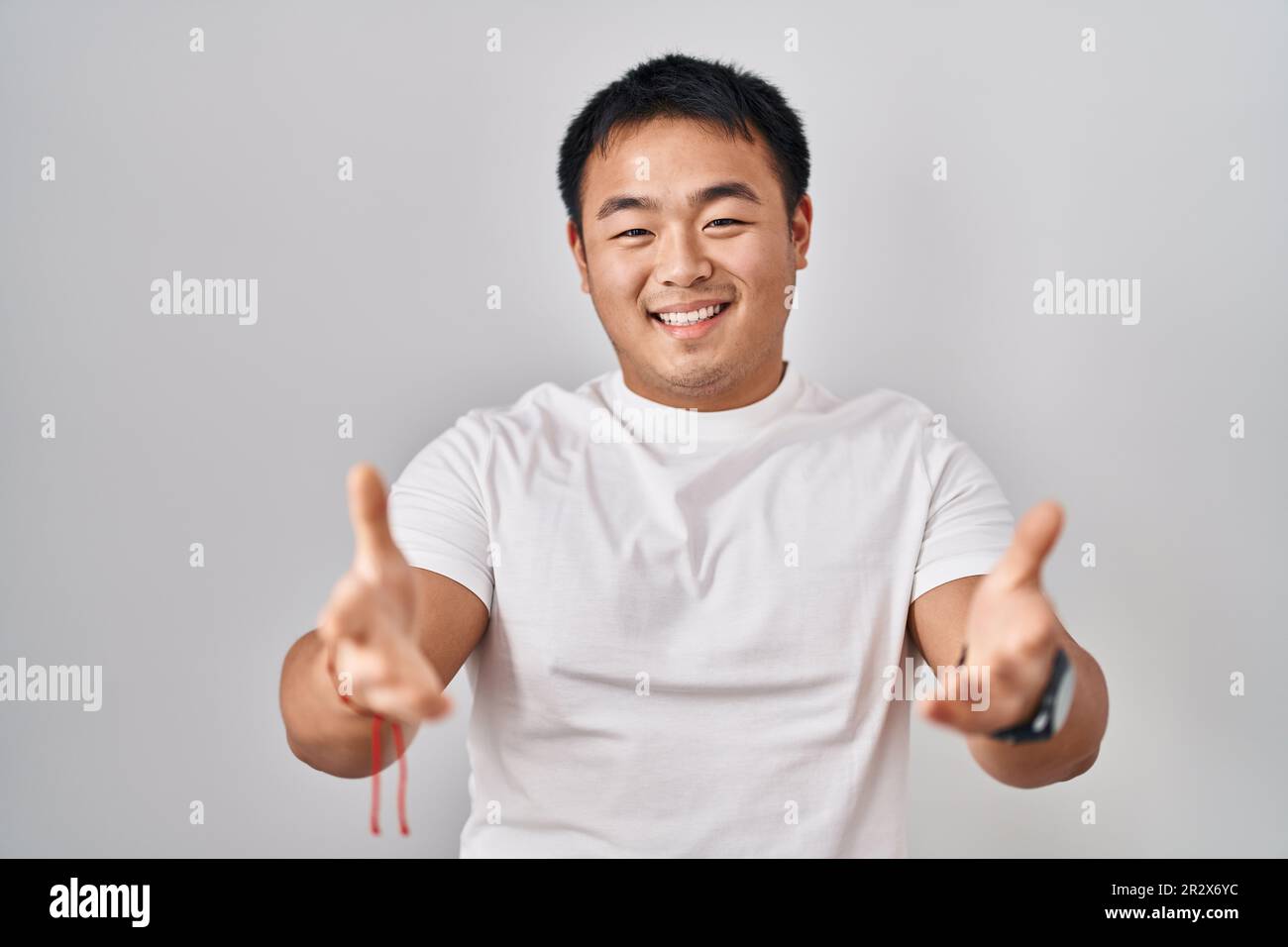 Young chinese man standing over white background smiling cheerful ...