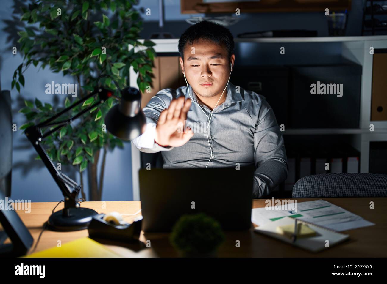 Young chinese man working using computer laptop at night doing stop ...