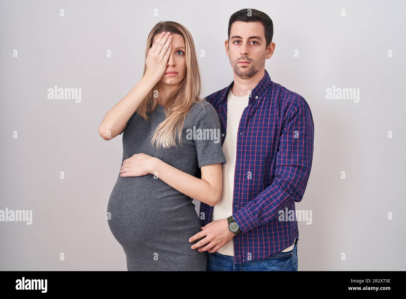 Young couple expecting a baby standing over white background yawning ...
