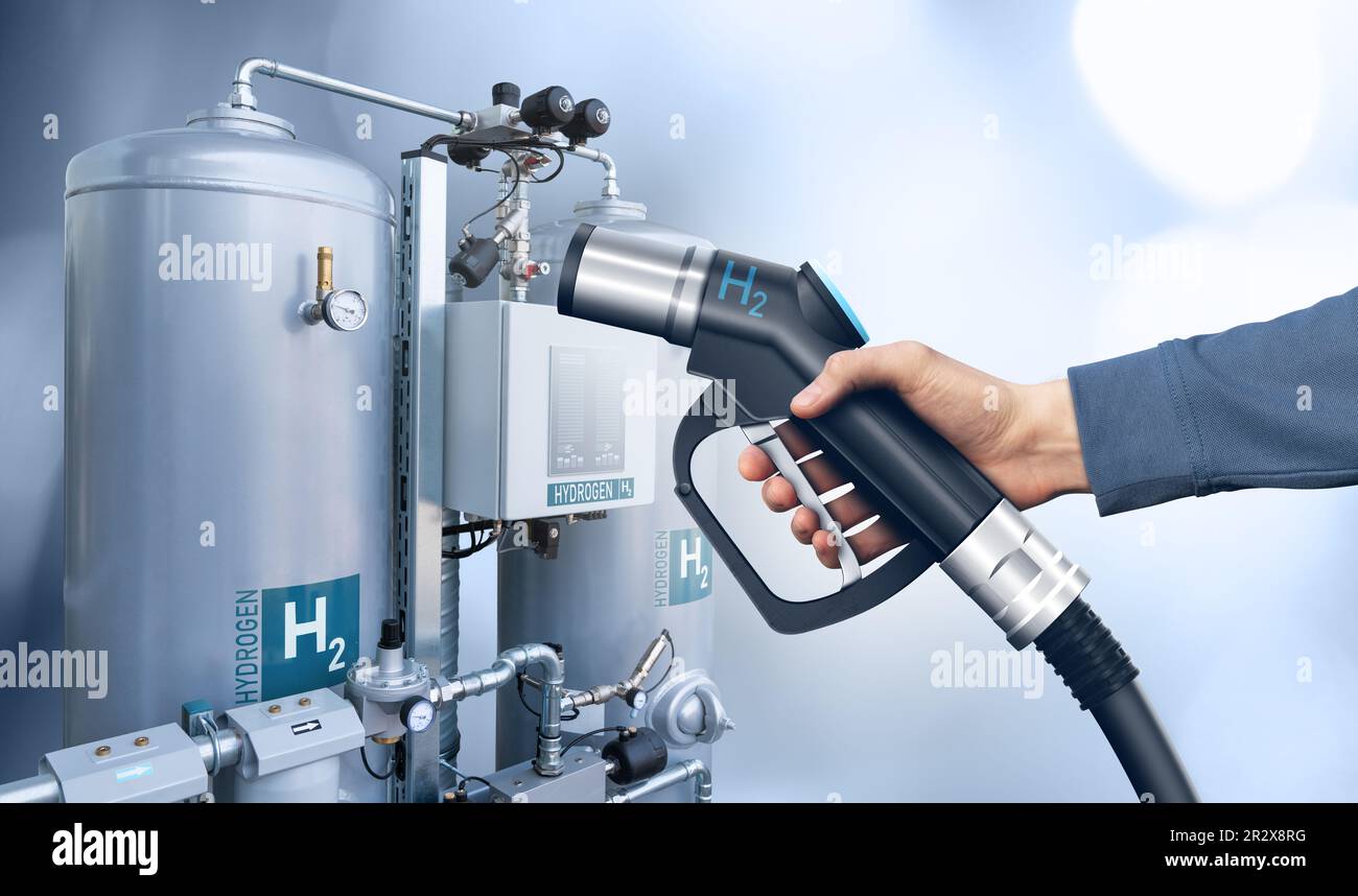 Hand with hydrogen fueling nozzle on a background of H2 factory ...