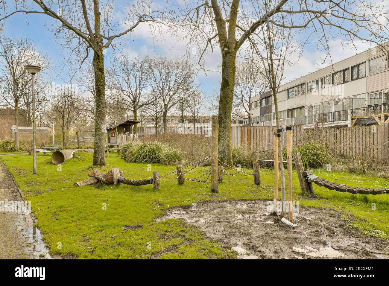 an empty yard with trees and trash bins on the ground in front of a row ...