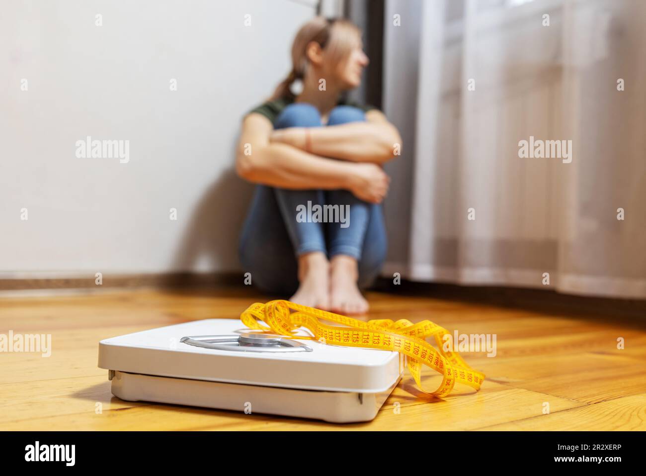 White scale with measuring tape and depression, upset woman sitting on floor Stock Photo - Alamy