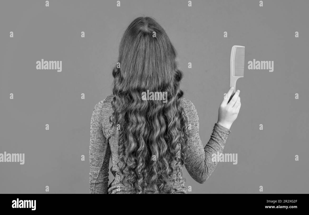 Back View Of Teen Girl With Curly Hair Hold Comb On Pink Background