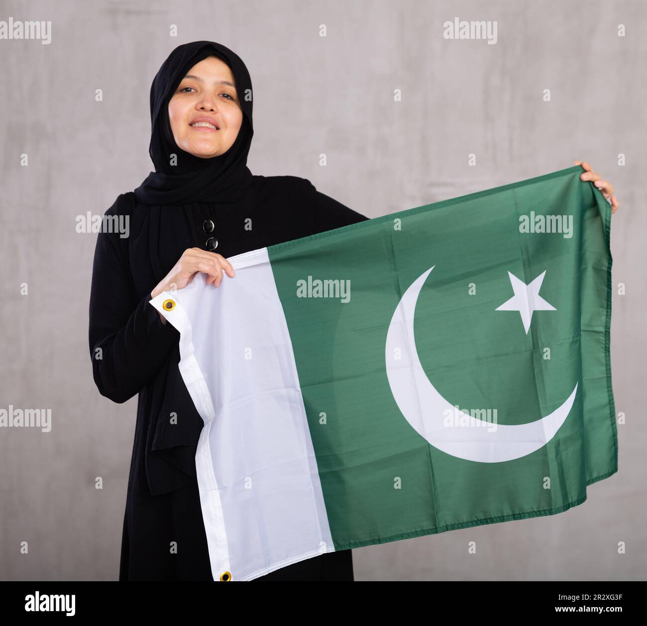 Young Muslim woman in black hijab holds unfurled flag of Pakistan Stock ...