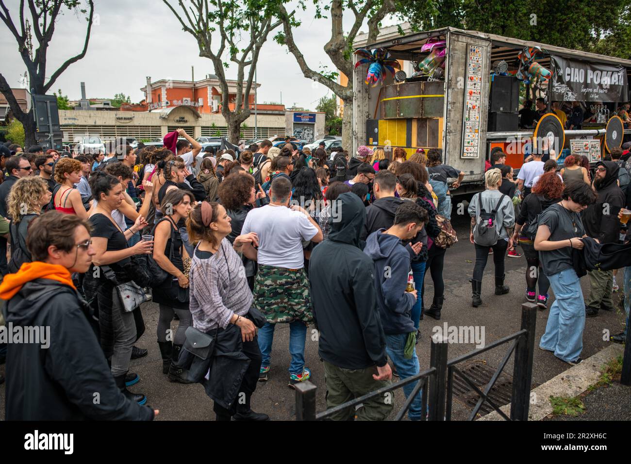 Boys and girls dance on the street behind and alongside trucks playing ...