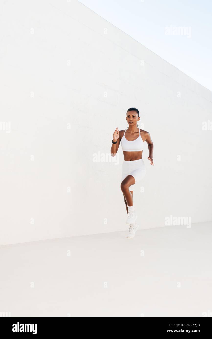 Slim female sprinter running outdoors. Full length of young sportswoman ...