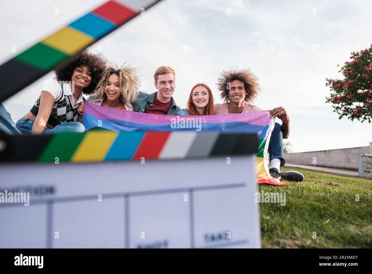 Group of friends sitting on the grass with lgtbi flag. Concept: pride ...