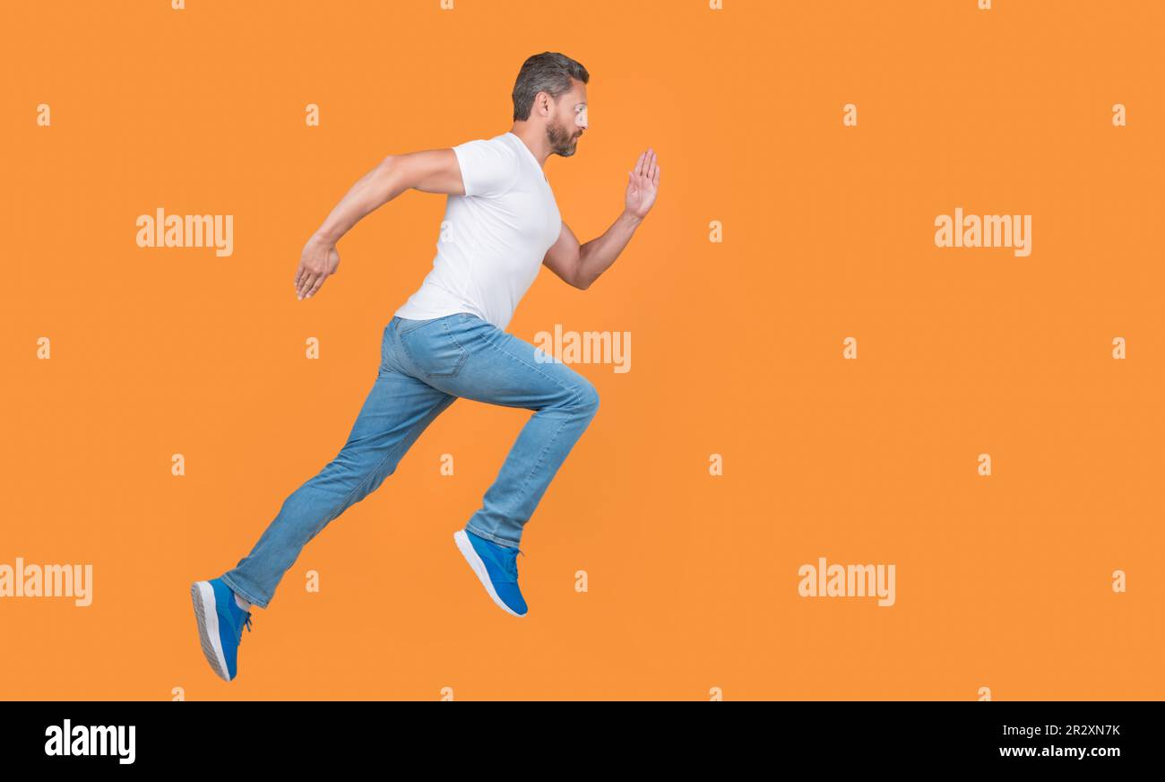 Energetic man running. Guy runner running on studio yellow background ...