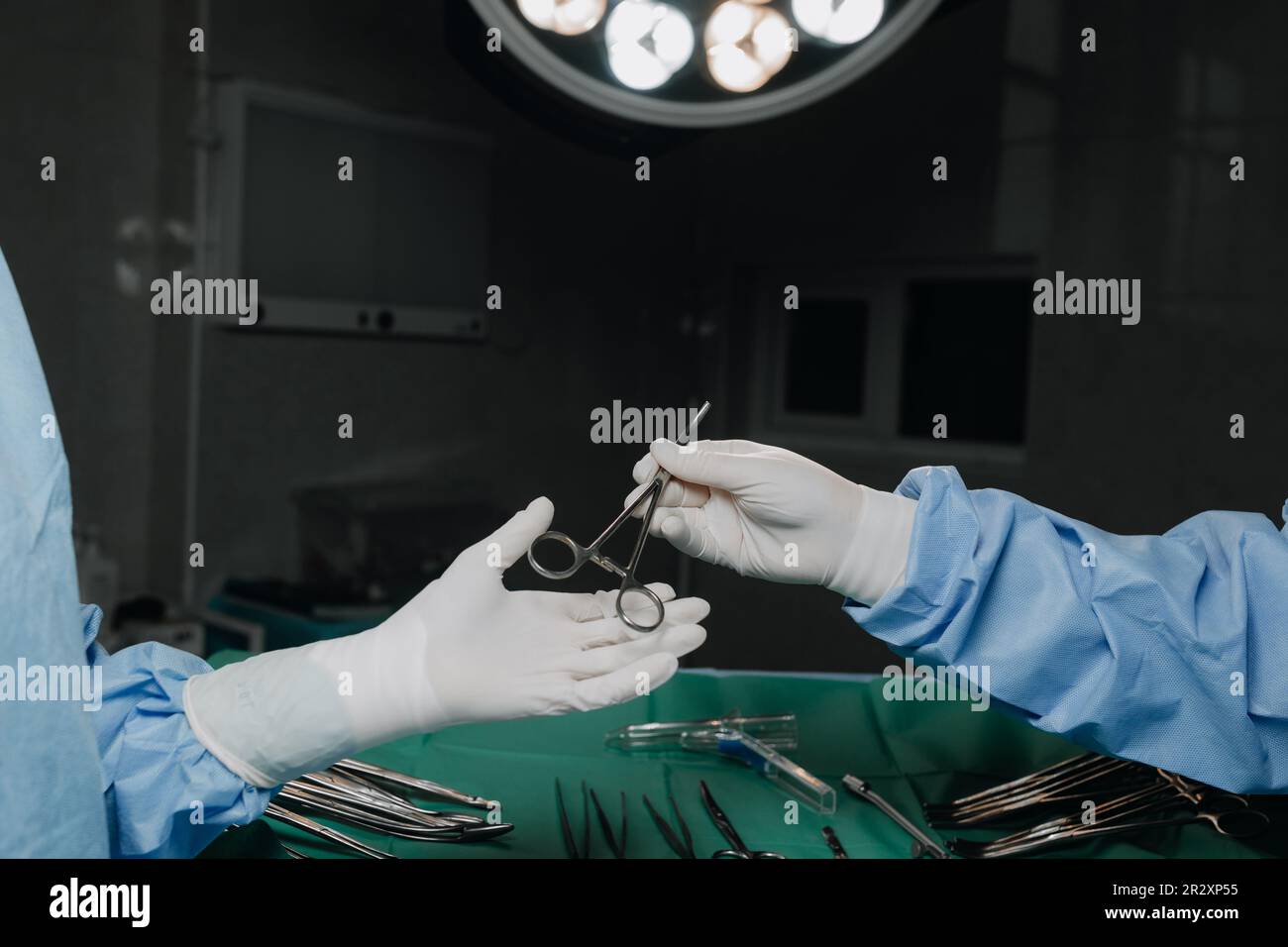 Low angle shot in operating room, assistant hands out tools to surgeons ...