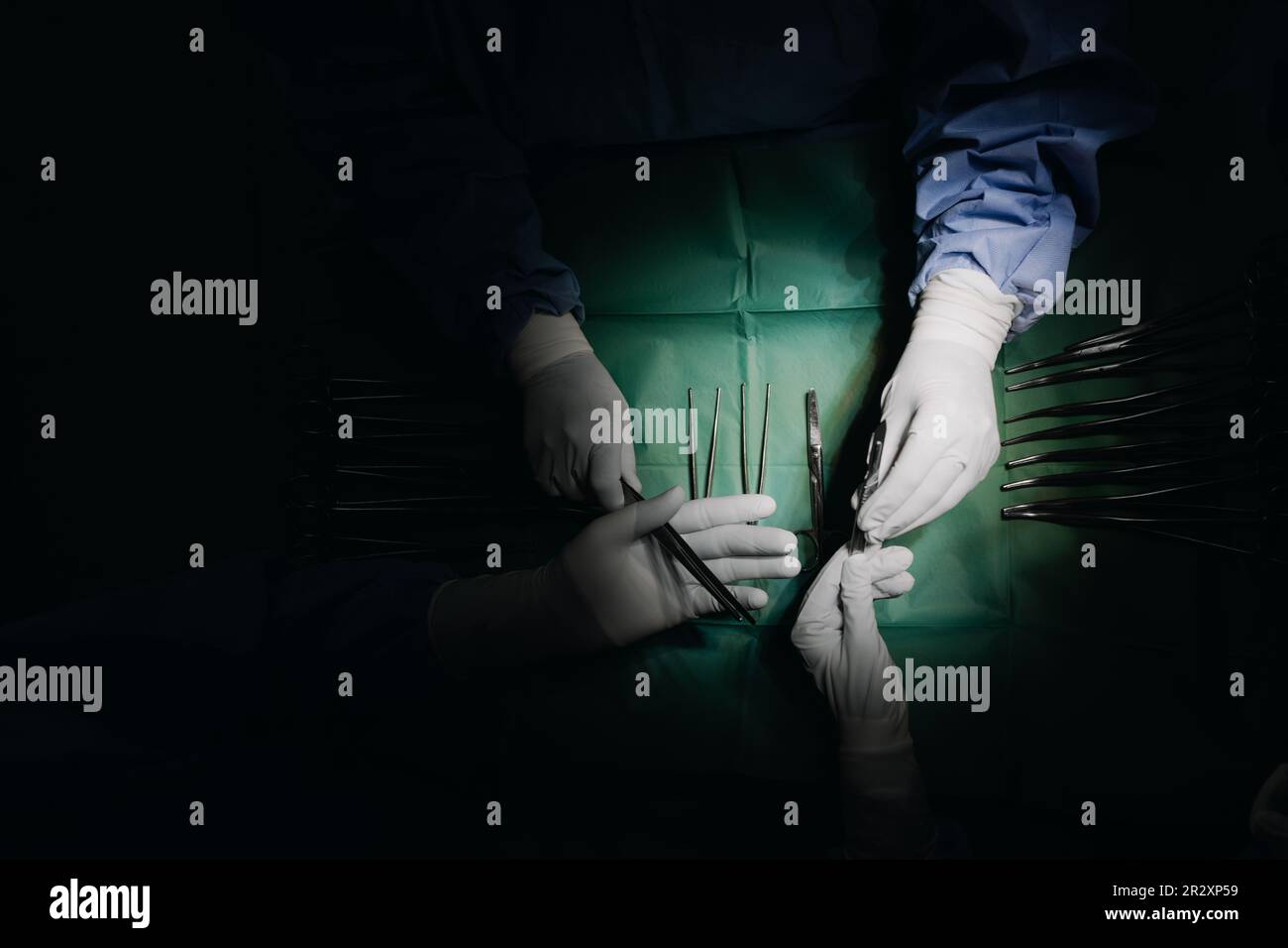 Low angle shot in operating room, assistant hands out tools to surgeons ...