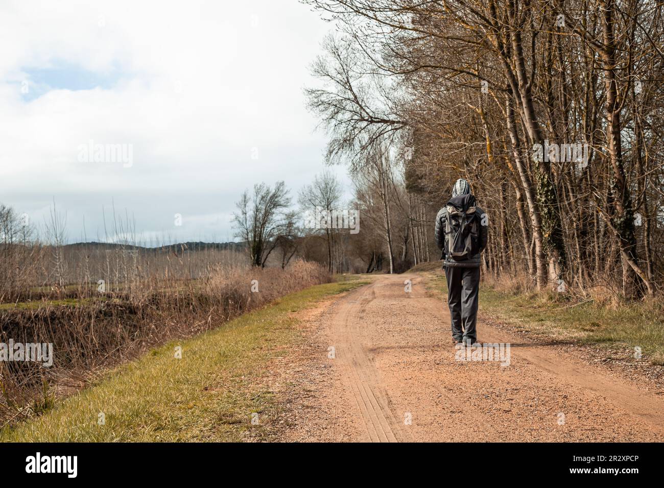 A boy is walking along a lonely path in an autumn landscape. He wears a ...